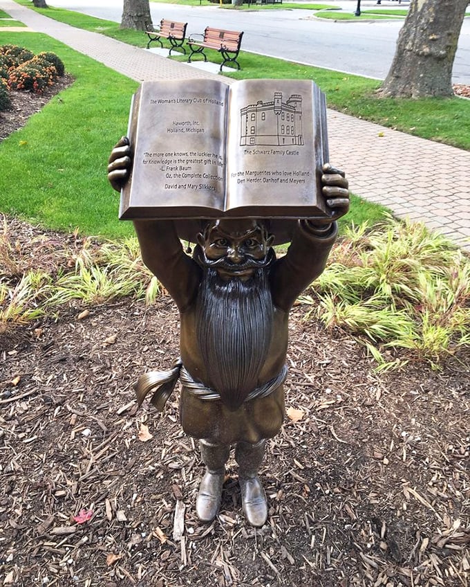 A whimsical munchkin holds aloft an open book, his detailed bronze features capturing the childlike wonder of Oz's smallest residents.