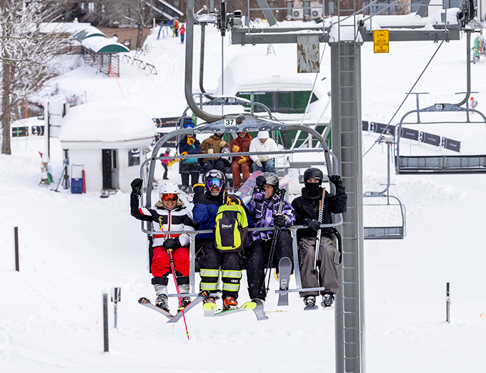 Happy adventurers celebrate another successful chairlift journey. Those smiles say it all: Michigan winters are for embracing, not escaping!