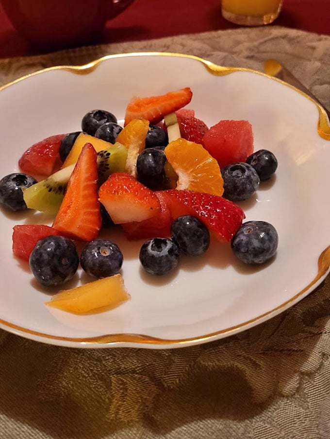 A colorful fruit medley served on gold-rimmed china &ndash; simple pleasures elevated through beautiful presentation and fresh, quality ingredients.