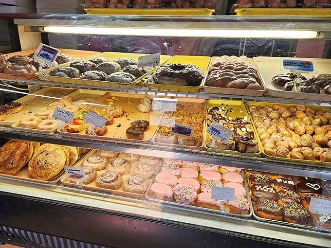 The display case – a museum of edible art where each pastry practically poses for its Instagram moment before meeting its delicious fate.
