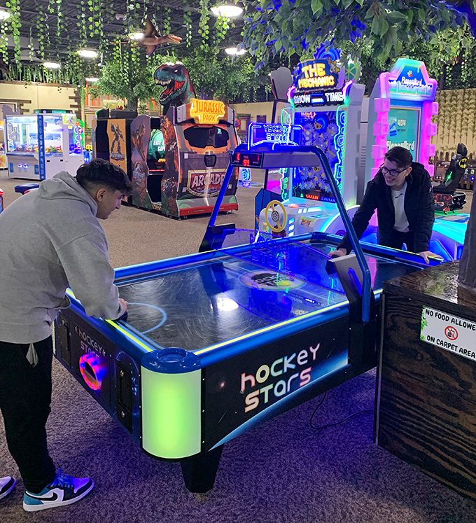 Air hockey brings out the competitive spirit in these players while a watchful T-Rex seems to referee from nearby. Game on!