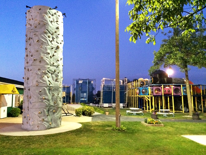 The climbing wall stands tall against blue skies, offering vertical challenges for those who've mastered the horizontal obstacles.