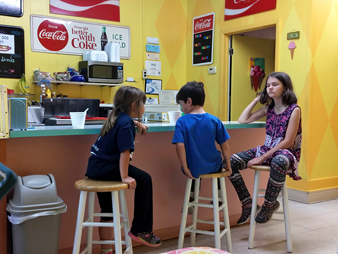 Young customers perched on stools, engaged in that timeless ritual of ice cream shop contemplation &ndash; serious business indeed.