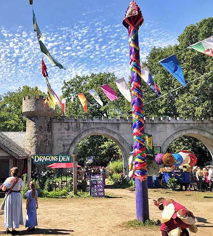 The festival's maypole area features colorful ribbons and flags, creating a vibrant gathering spot where traditional dances celebrate ancient seasonal rituals.