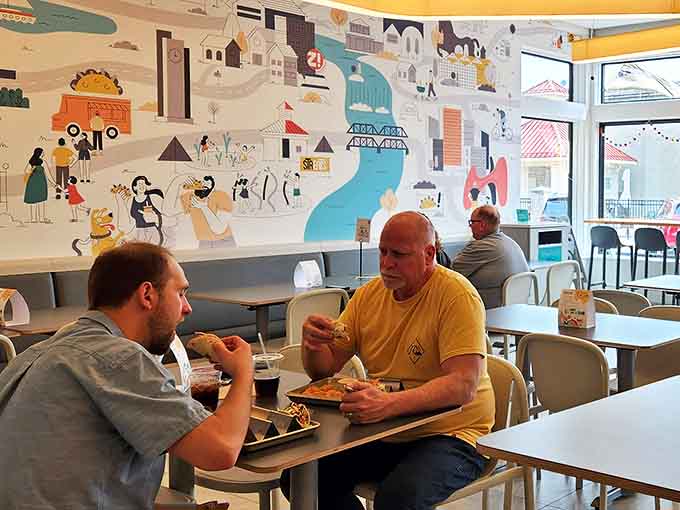 Happy diners enjoying their taco feast against the backdrop of that magnificent mural &ndash; proof that good food creates its own atmosphere.