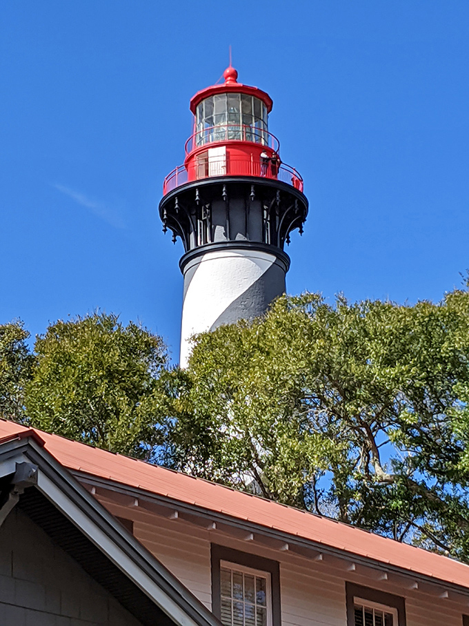 The lighthouse's bold stripes create a striking contrast against blue skies, a design that makes it recognizable to sailors miles offshore.