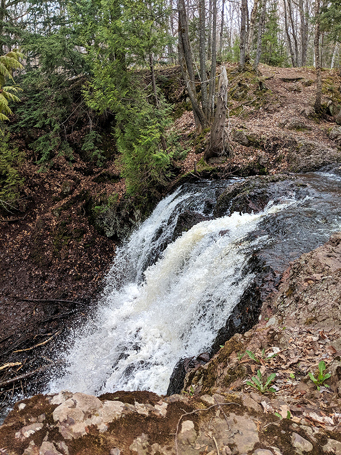 This hidden cascade tumbles through layers of ancient stone, telling geological stories that span millions of years in a single glance.