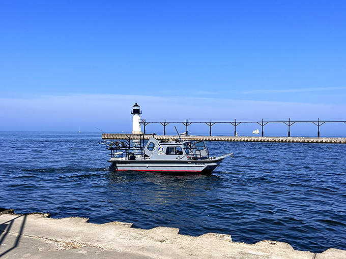 A small fishing boat navigates the calm waters near the lighthouse &ndash; the perfect Michigan morning for both serious anglers and casual sightseers.