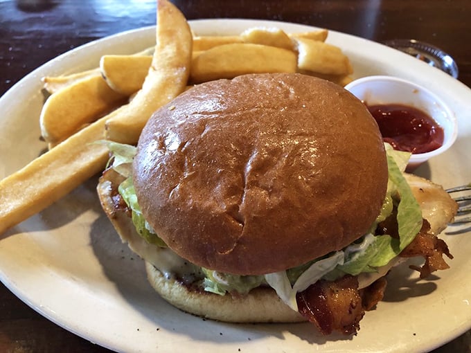 A burger that requires both hands and a strategy, flanked by fries that achieve the golden ratio of crispy exterior to fluffy interior.