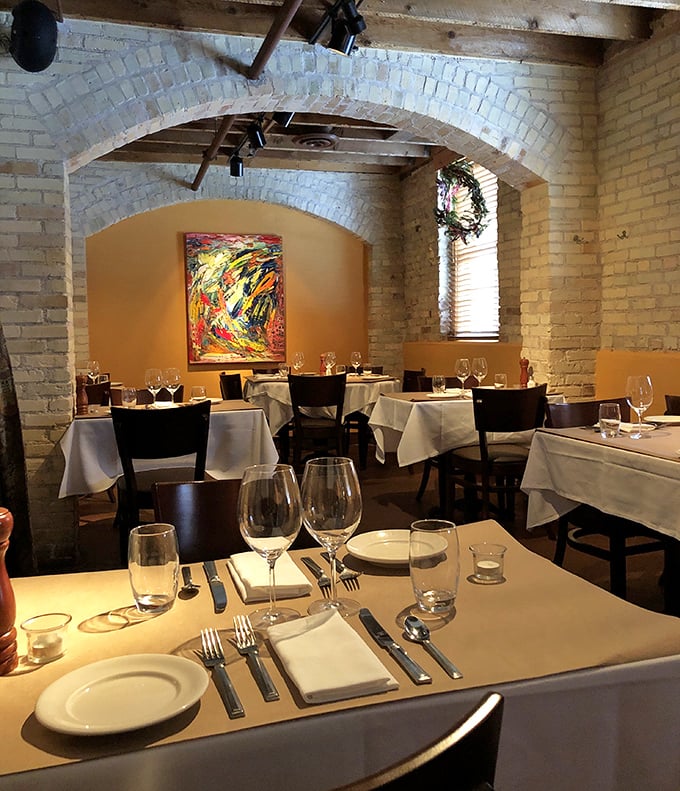 White tablecloths and exposed brick create dining spaces where conversations flow as smoothly as the wine.