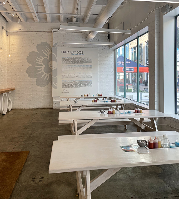 White picnic tables bathed in natural light create the perfect backdrop for the colorful Cuban-inspired feast that's about to unfold.