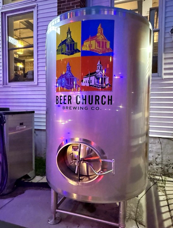 The modern-day baptismal font where beer is born, illuminated by colorful lights against the historic white church exterior.