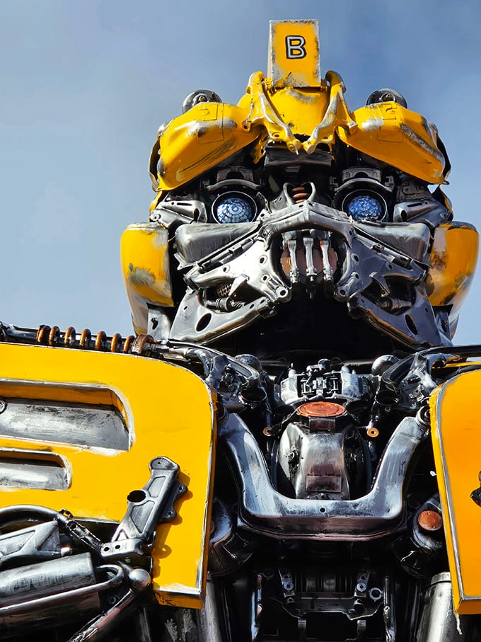 Mack-A-Tron's face combines automotive headlights and grillwork into an expressive visage that seems almost alive, watching over the bustling shopping district below.