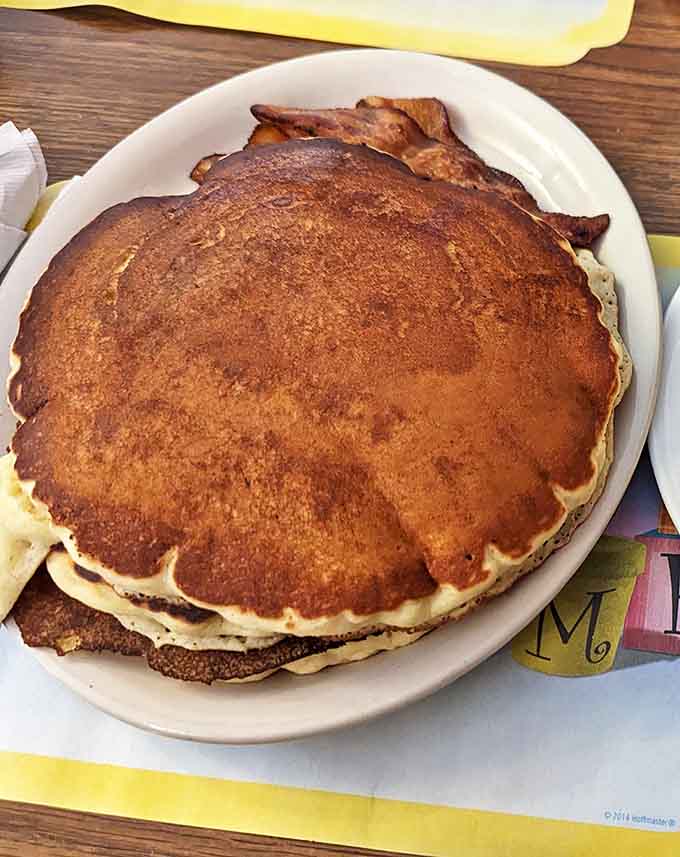 Pancakes so perfectly golden they practically glow, stretching to the plate's edge and begging for maple syrup.