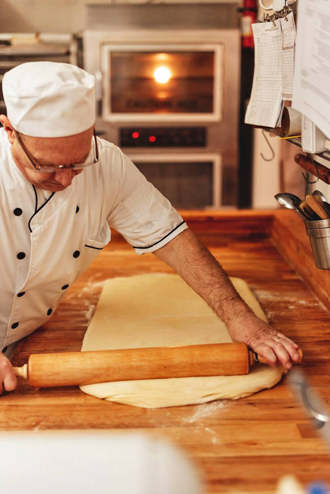 Behind every perfect pastry is a skilled baker, rolling dough with the practiced precision that comes from dedication to craft rather than mass production.