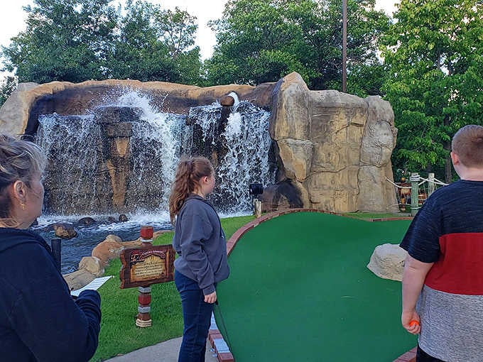Visitors pause to admire the waterfall feature, a refreshing oasis that provides both scenic beauty and welcome cooling on summer days.
