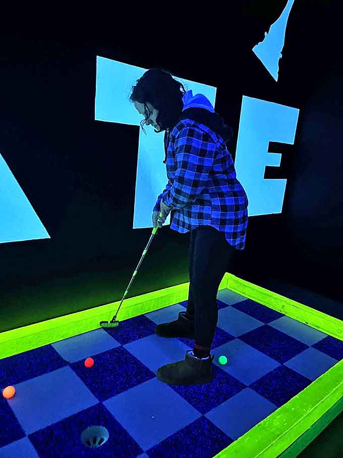 Woman Playing Golf Concentration is key as this player navigates the glowing checkerboard pattern, proving mini-golf is serious business&mdash;even in neon wonderlands.