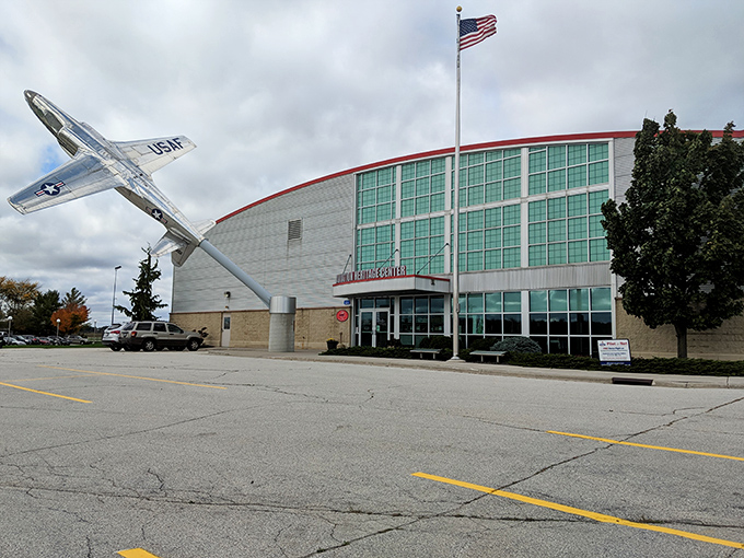 The Aviation Heritage Center's striking exterior features a sleek silver aircraft dramatically mounted as if frozen mid-flight against Wisconsin's changeable skies.