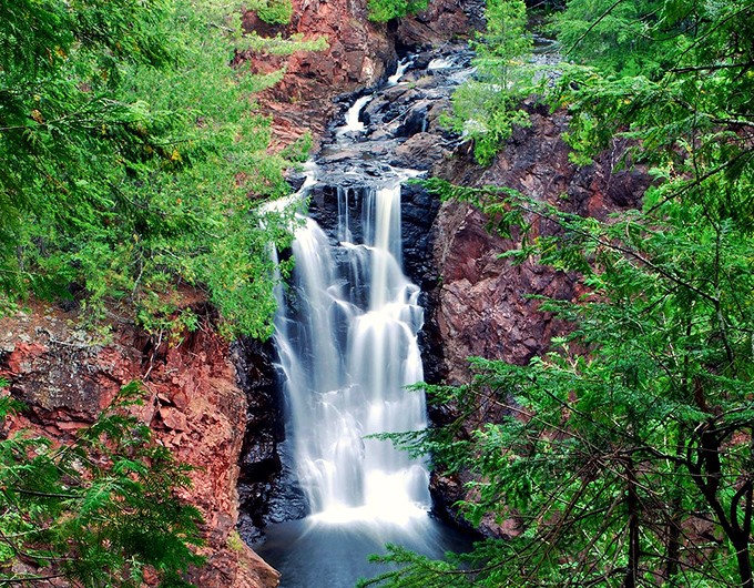 Brownstone Falls puts on nature's ultimate magic show, where water dances down reddish cliffs like it's auditioning for Broadway.