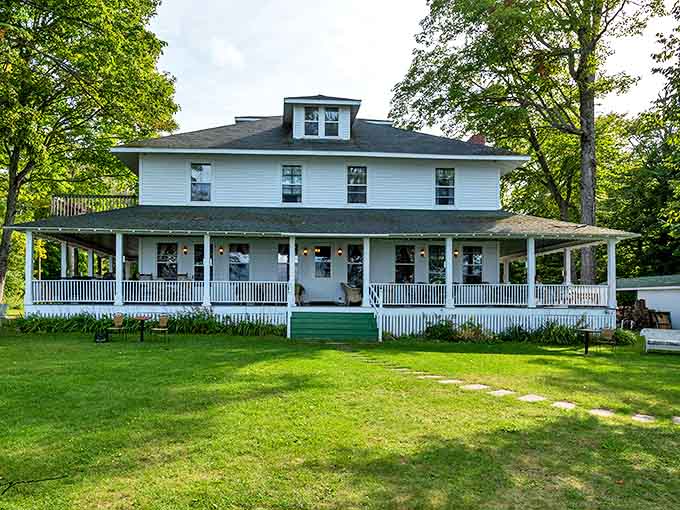 Classic white clapboard elegance meets lakeside charm at Chamberlin's Ole Forest Inn, where the wraparound porch beckons weary travelers home.