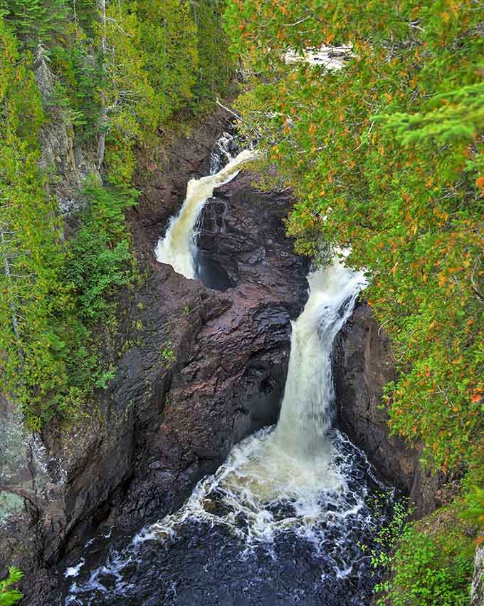 Nature's magic trick in action: Devil's Kettle waterfall plunges dramatically into its mysterious underground chamber, surrounded by Minnesota's lush forest canopy.