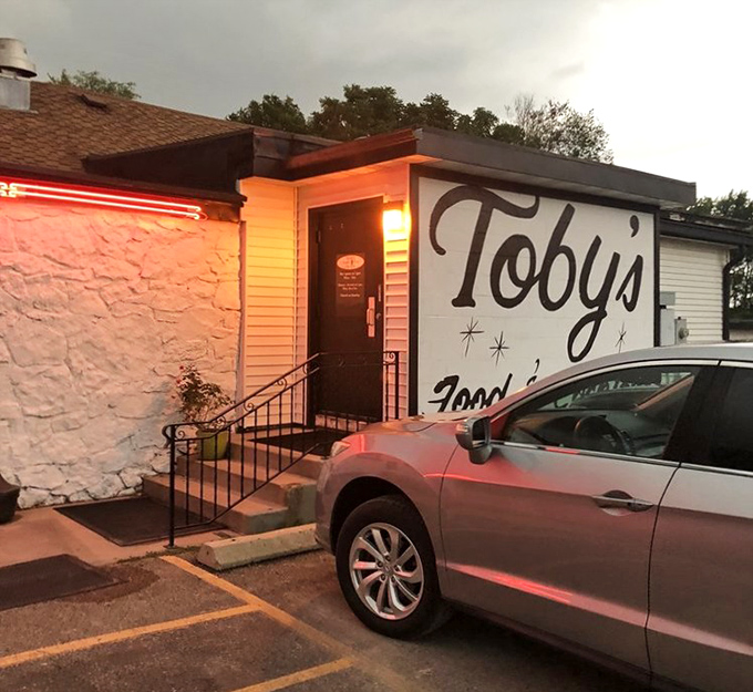 The iconic exterior of Toby's Supper Club glows with welcoming neon, promising old-school delights within those unassuming walls.