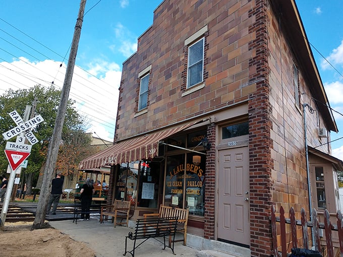 A brick time machine with a striped awning – J. Lauber's exterior promises sweet nostalgia beside vintage railroad crossing signs.