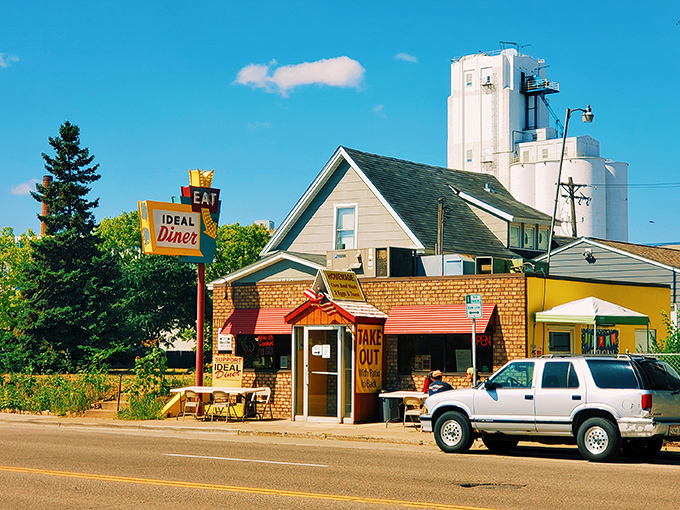 The iconic yellow and brick exterior of Ideal Diner stands proudly against the Minneapolis sky, its vintage "EAT" sign beckoning hungry travelers for generations.