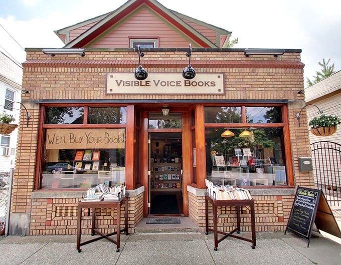 The inviting brick façade of Visible Voice Books promises literary adventures with its charming "We'll Buy Your Books!" window sign.