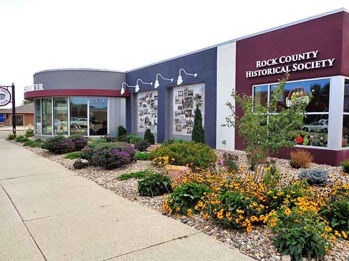 The welcoming facade of Rock County Historical Society blooms with colorful flowers, hiding the wooden wonders within.