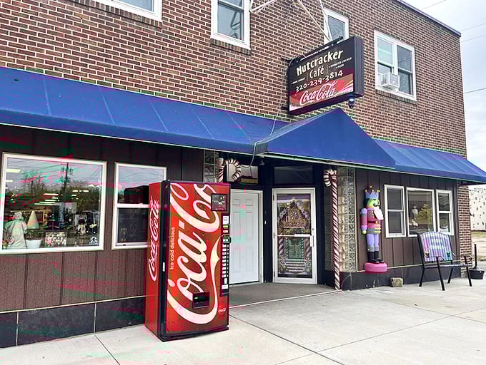 The cheerful blue awnings and life-sized nutcracker guardian create an inviting entrance that promises holiday magic inside, no matter the season.