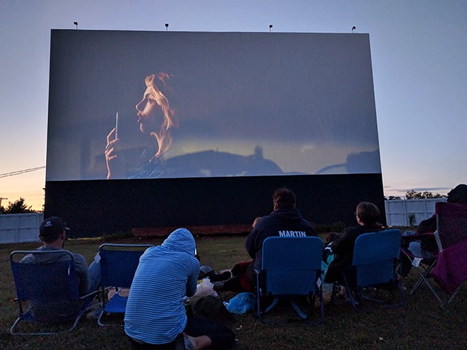 The massive screen at Mayfield Road Drive-In stands tall against the twilight sky, a beacon of nostalgia calling movie lovers home.