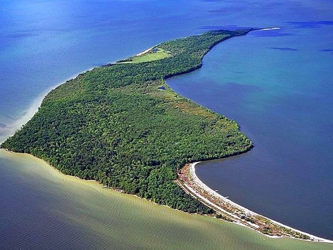 An aerial view of Garden Island's distinctive curved shape, embracing the blue waters of Lake of the Woods like a protective arm.