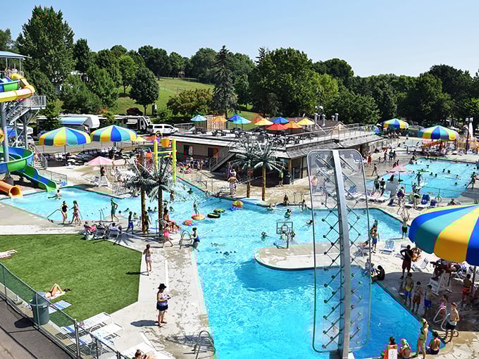 Aerial view of summer paradise where Minnesota families have been creating chlorine-scented memories for generations. The waterpark sprawls invitingly under blue skies.
