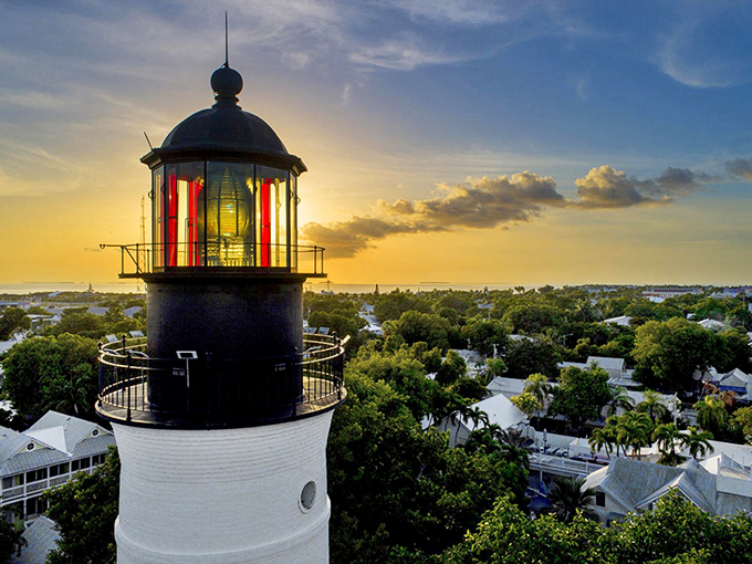 The Key West Lighthouse stands proudly against a sunset sky, its beacon glowing with history and promise of spectacular views ahead.