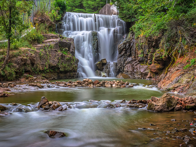 Nature's perfect curtain: Lake Redstone Waterfall cascades with hypnotic rhythm, turning ordinary rocks into a masterpiece of flowing artistry.