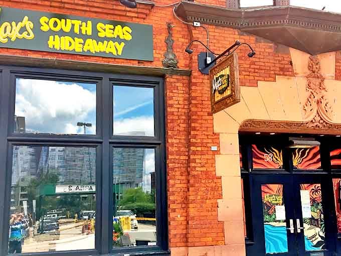 The brick facade of Max's South Seas Hideaway beckons with golden lettering and vibrant doors, promising tropical escape in downtown Grand Rapids.