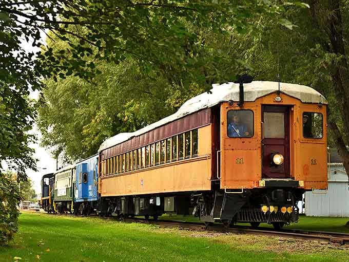 The vibrant orange passenger car of the Michigan Transit Museum stands ready for adventure, a rolling time capsule from railroading's golden age.