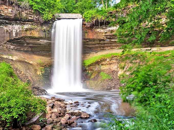 Minnehaha Falls cascades 53 feet in a perfect white ribbon, nature's own masterpiece tucked into the heart of Minneapolis.
