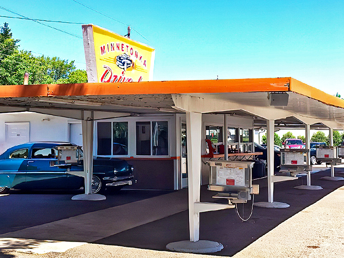 The iconic yellow Minnetonka Drive In sign stands tall against the blue Minnesota sky, a beacon of nostalgia that's drawn hungry travelers for generations.
