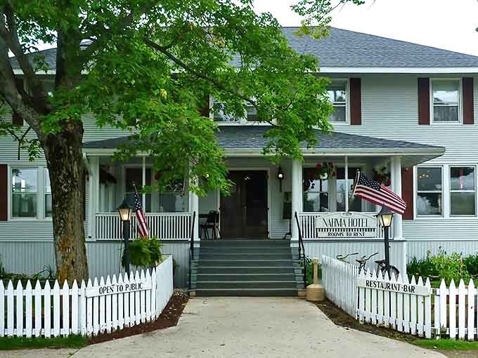 The classic white clapboard exterior of Nahma Inn welcomes visitors with its timeless charm and inviting front porch.