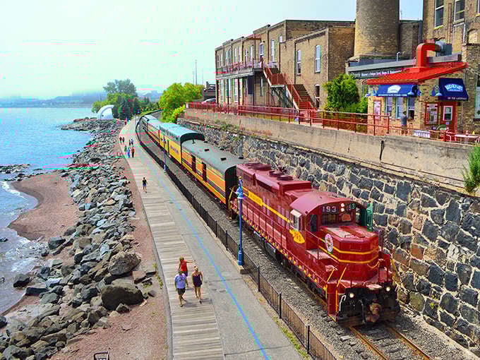 The crimson locomotive cuts a striking figure against Lake Superior's blue expanse, like a time traveler from railroading's golden age.