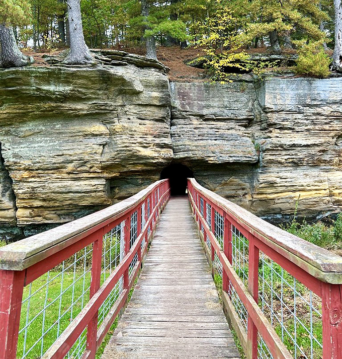 A red footbridge leads into darkness, promising adventure through solid rock&mdash;nature's version of a secret passage.