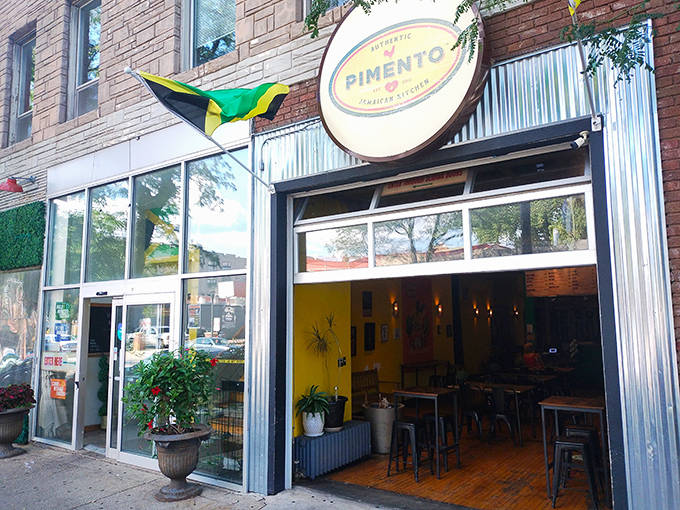 The vibrant exterior of Pimento Jamaican Kitchen, with its proud Jamaican flag fluttering like a tropical beacon in Minneapolis.