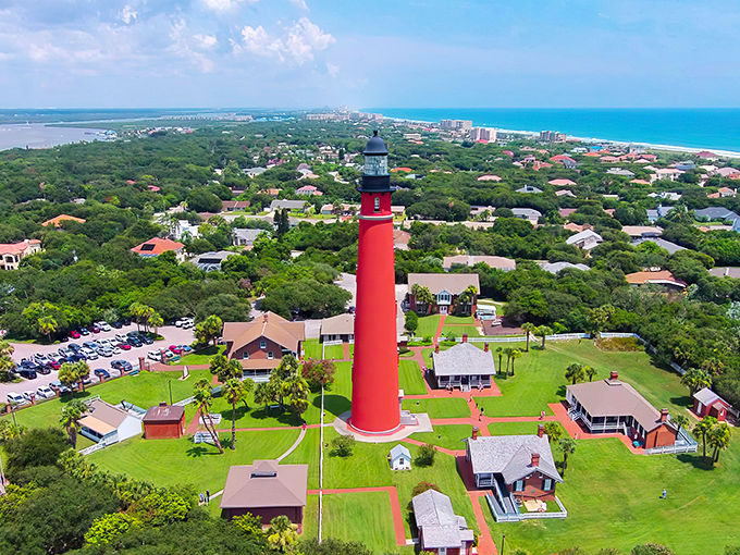 Like a crimson exclamation point on Florida's coastline, this aerial view showcases the lighthouse standing proud among the lush greenery, with the Atlantic Ocean stretching beyond.