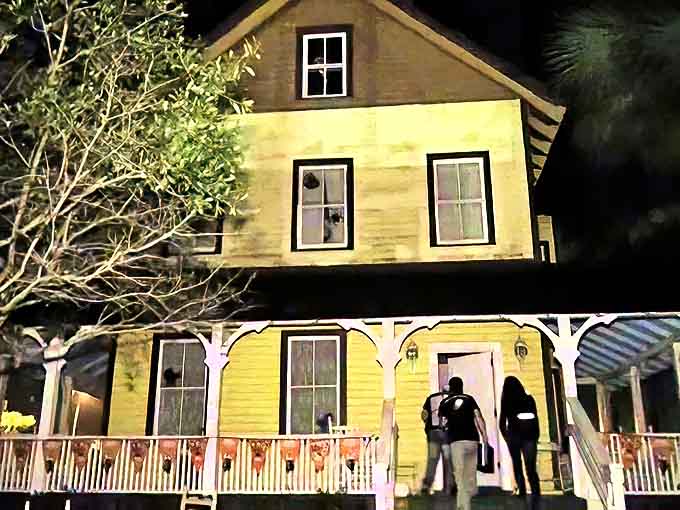 The Riddle House stands illuminated against the night sky, its yellow facade hiding a century of secrets and supernatural tales.