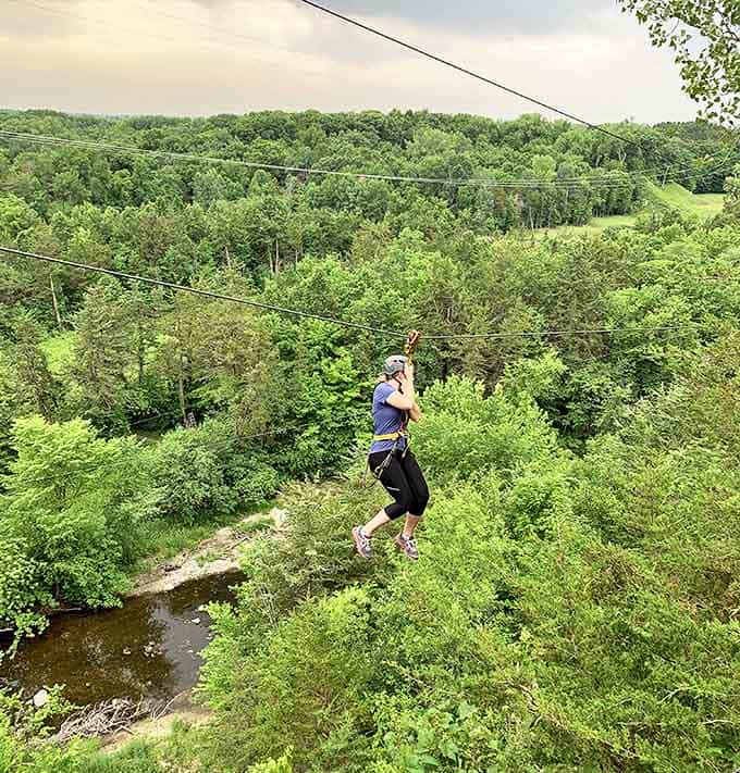 A daring adventurer suspended mid-air above Sand Creek, proving that flying without wings is possible with enough courage and a sturdy cable.