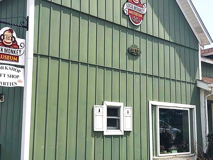 The charming green exterior of the Sock Monkey Museum beckons visitors with its playful signage and cozy cottage vibe.