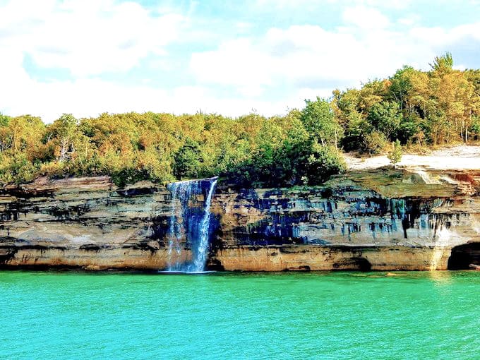 Nature's perfect plunge: Spray Falls cascades 70 feet from ancient sandstone cliffs into Lake Superior's turquoise waters, creating a misty spectacle worth every step of the journey.