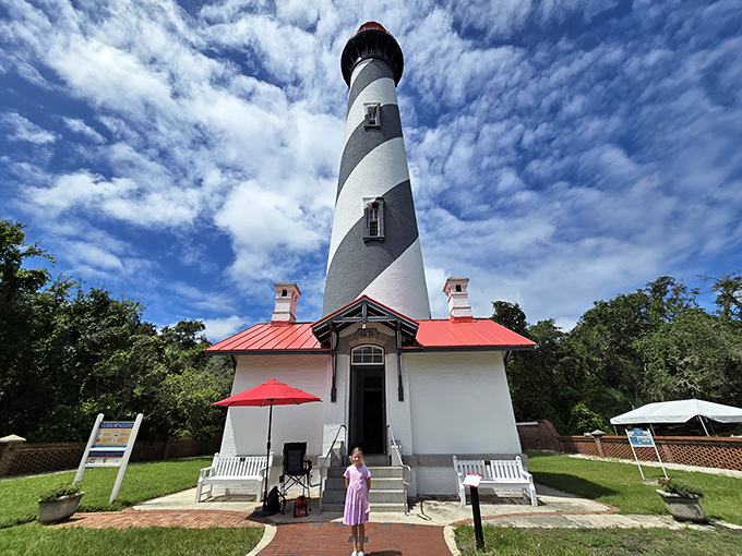 The iconic St. Augustine Lighthouse stands proudly against a cloud-dappled sky, its black and white spiral pattern beckoning visitors to explore its 165-foot height.